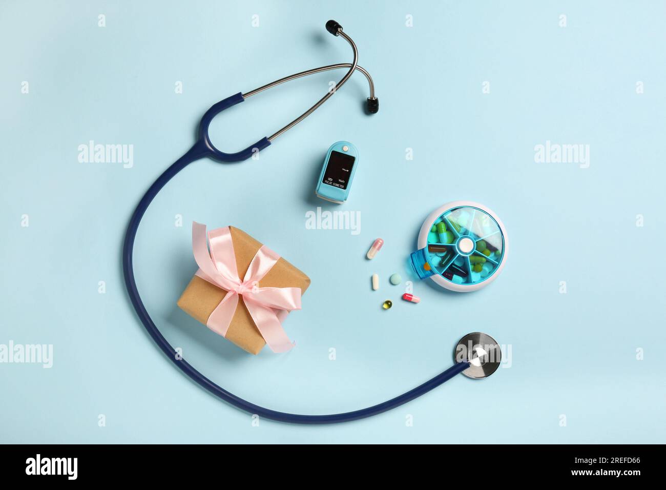 Stethoscope, pills, box and pulse oximeter on light blue background ...