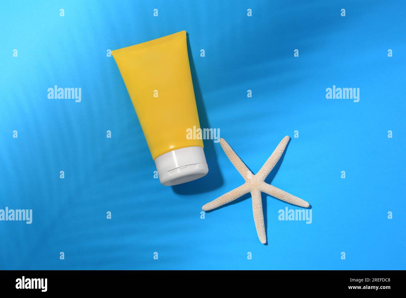 Sunscreen and starfish on light blue background, flat lay. Sun ...