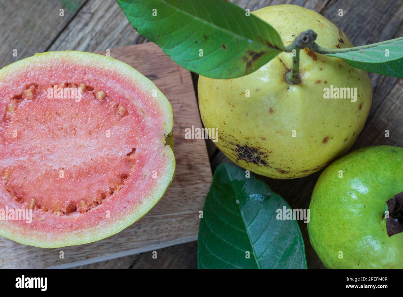 Fresh red guava with green leaves on wooden background. Texture of wood ...