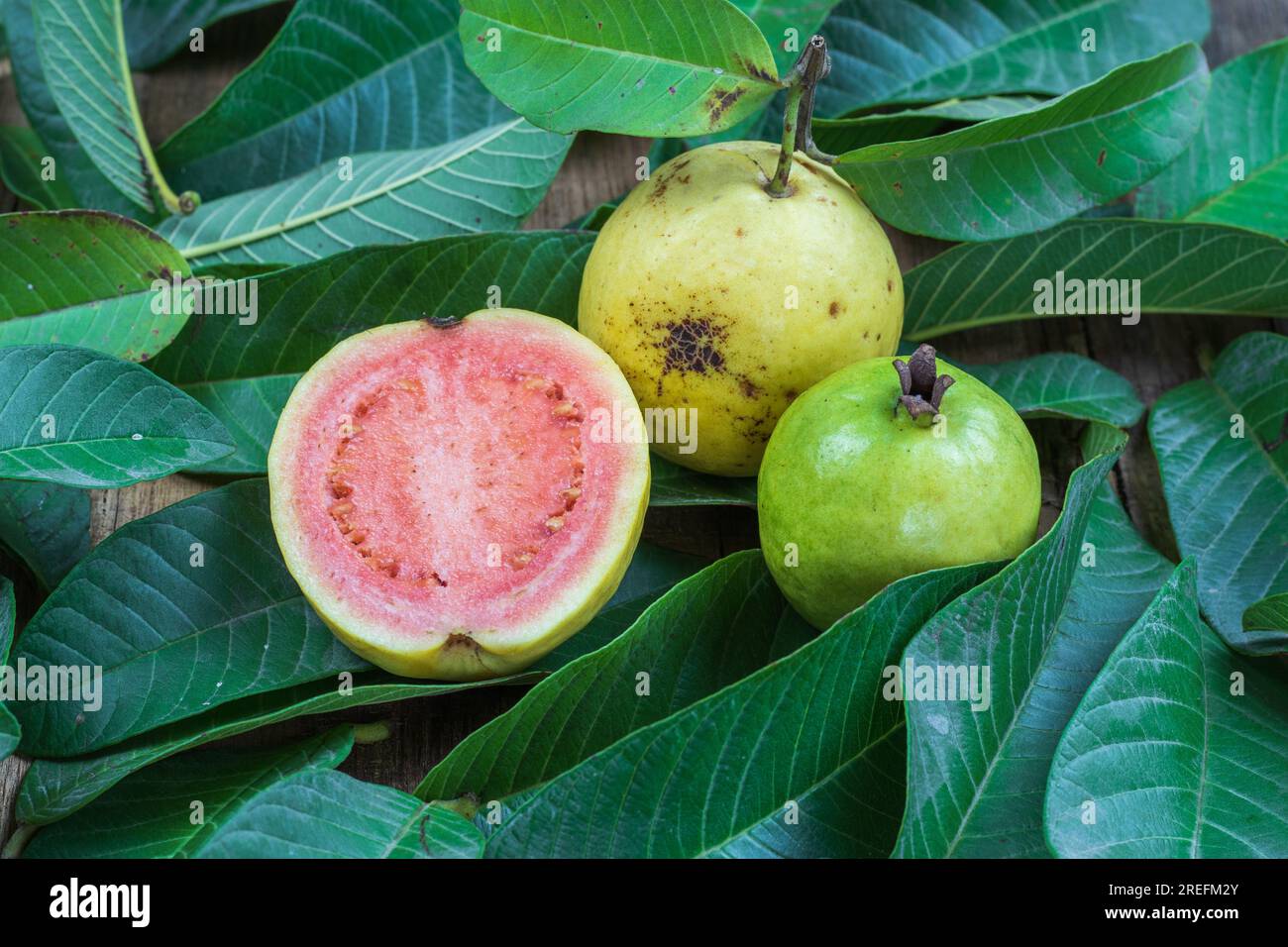 Fresh red guava with green leaves on wooden background. Texture of wood ...