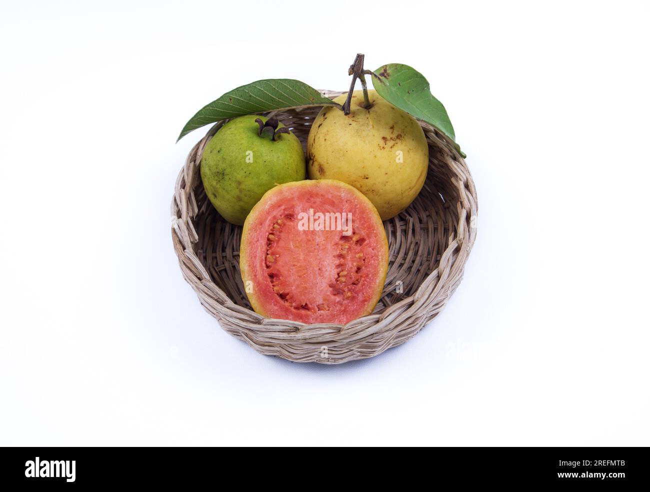 Isolated fresh red guava in a woven bamboo basket with green leaves ...