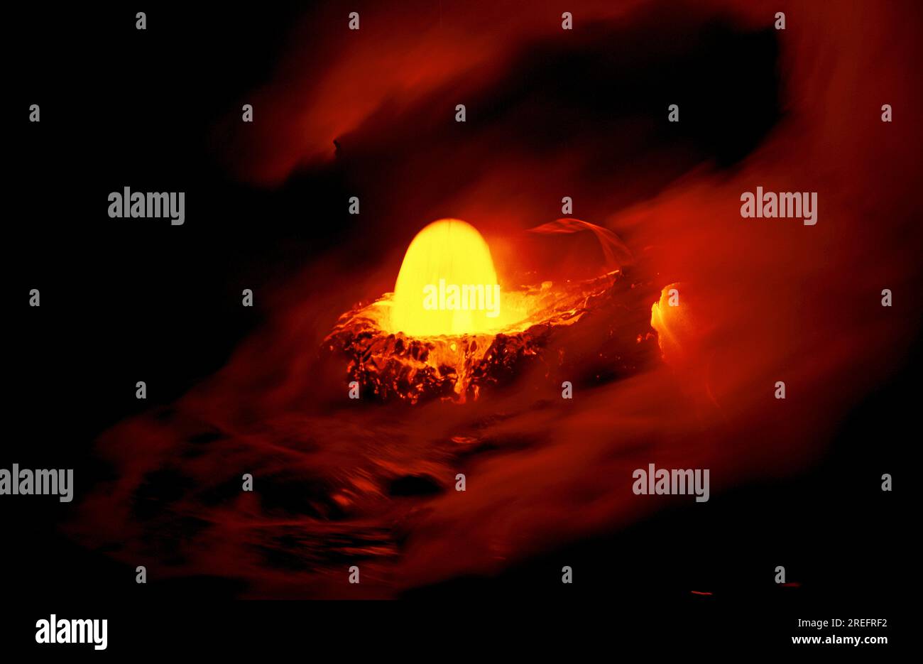 A dome of bright yellow fiery lava rises from a swirl of red molten ...