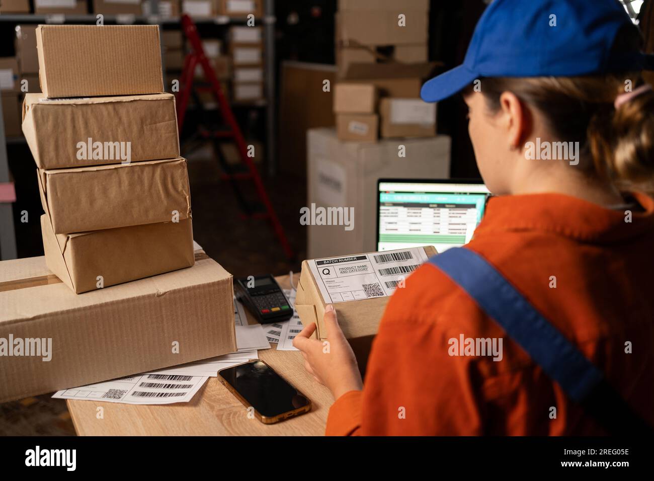 Storehouse worker. Young woman putting labels on products while working ...