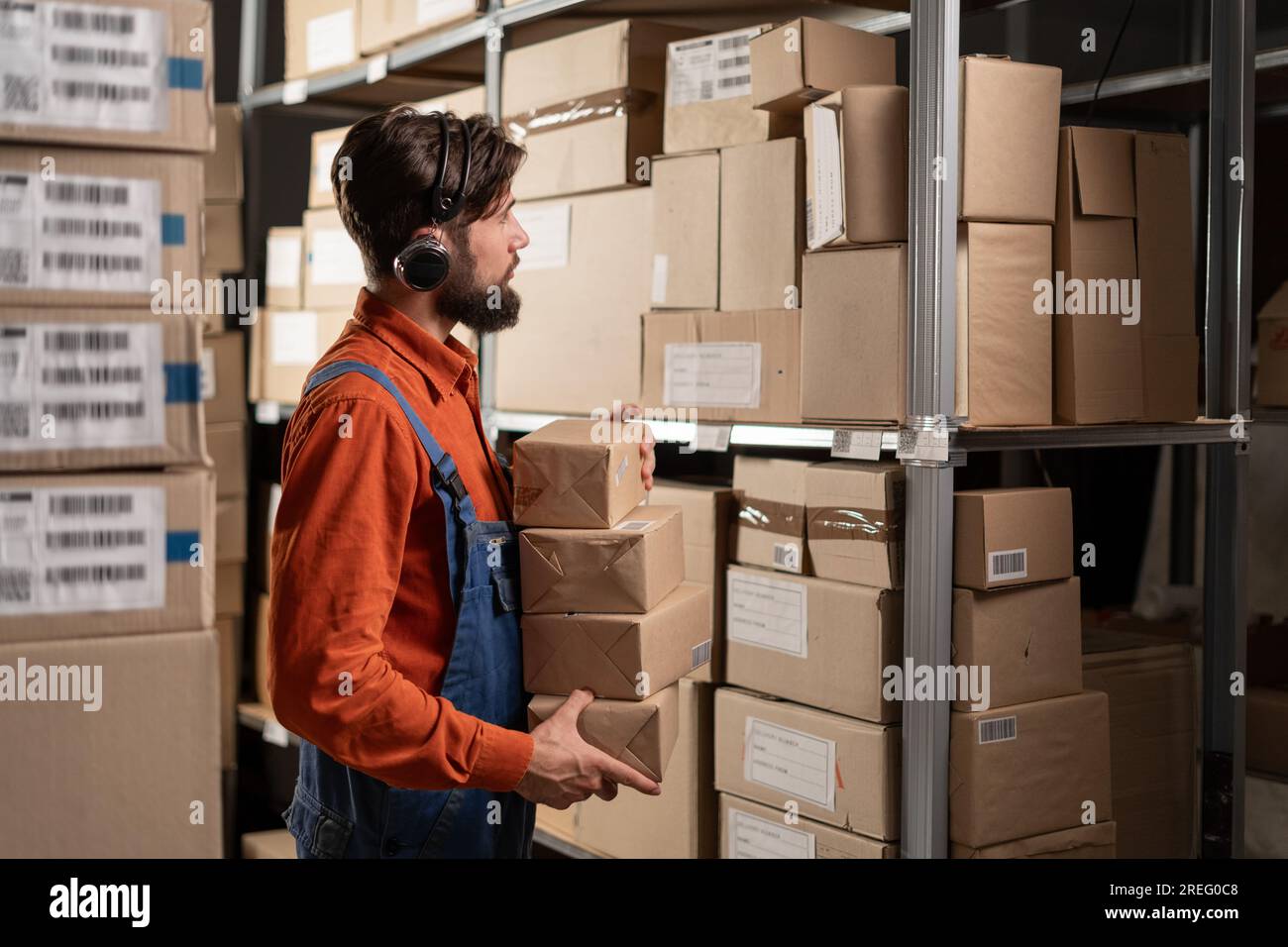 Working at warehouse. Warehouse worker holding boxes near the shelf ...
