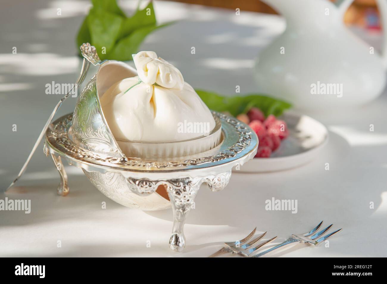 Burrata cheese in antique dishes with red and yellow raspberries Stock ...