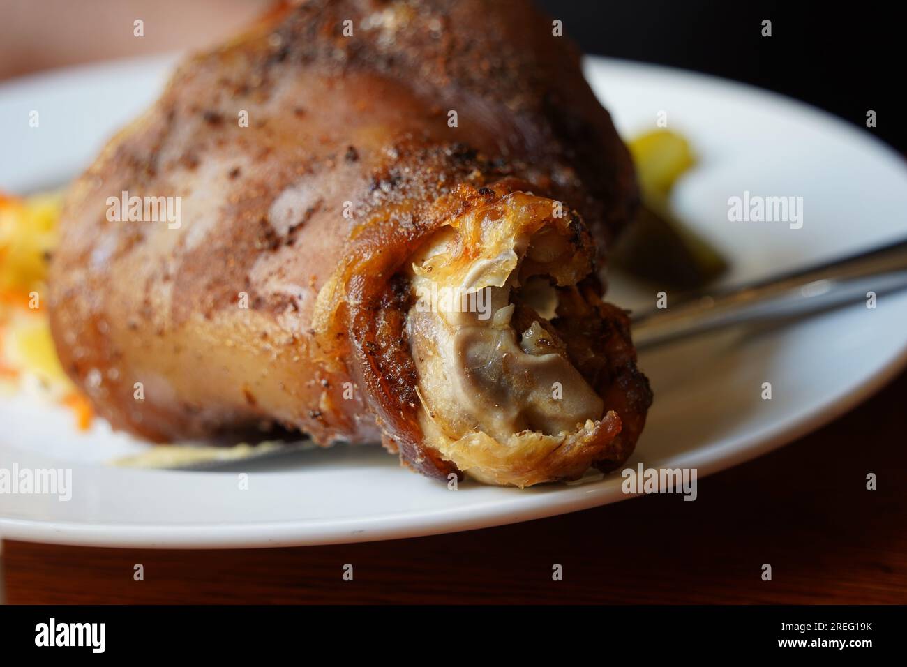 Roasted pork knuckle, pork knee served with pickled cucumbers and herbs ...