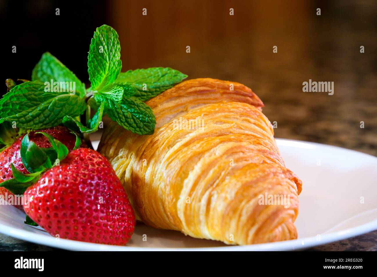 on a plate two delicious appetizing fresh croissants with strawberries ...