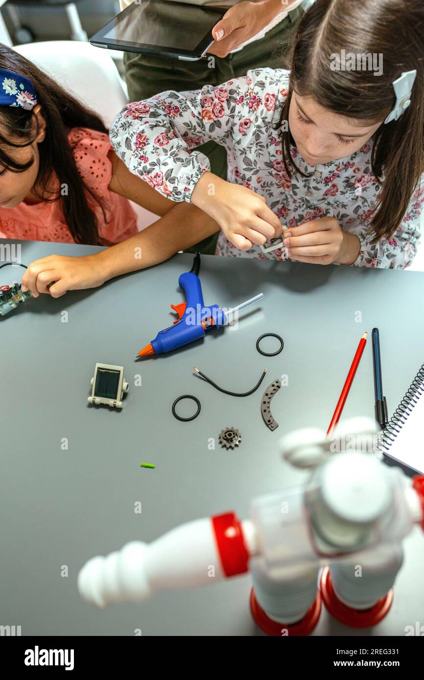 Student assembling machine pieces next to her teacher and to ...