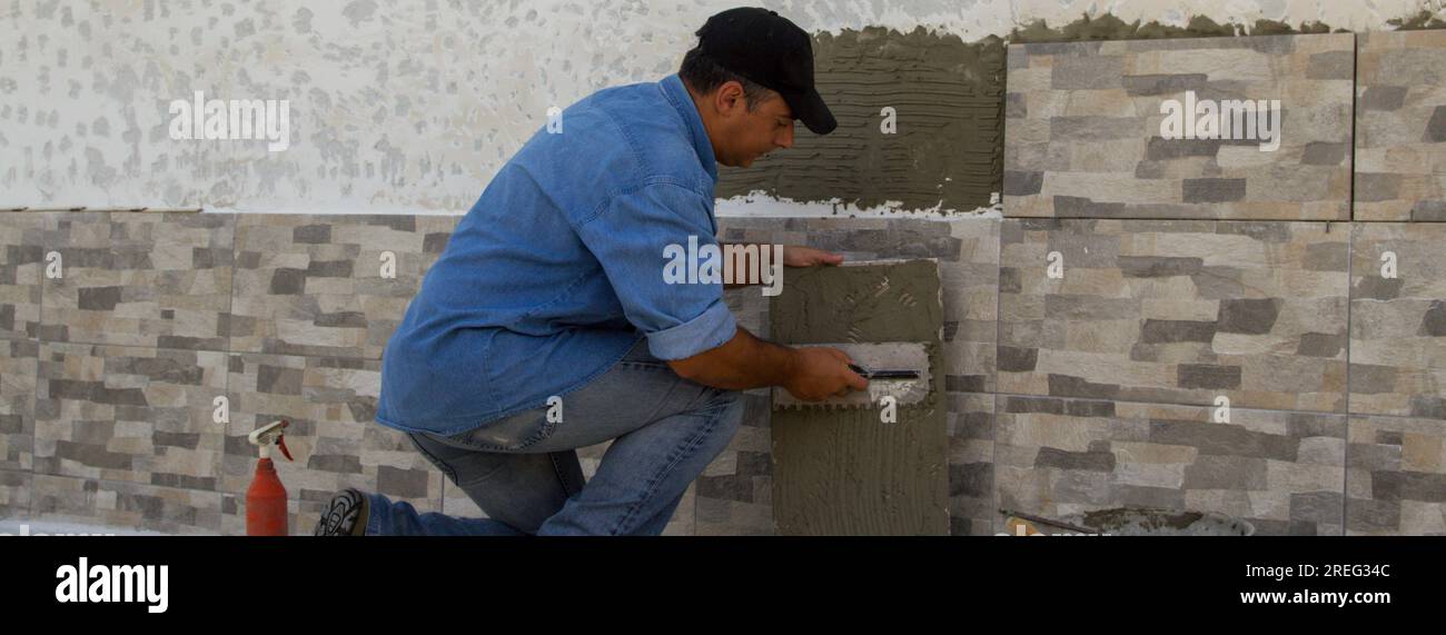 Image of a handyman tiler who with a spatula spreads the glue for ...