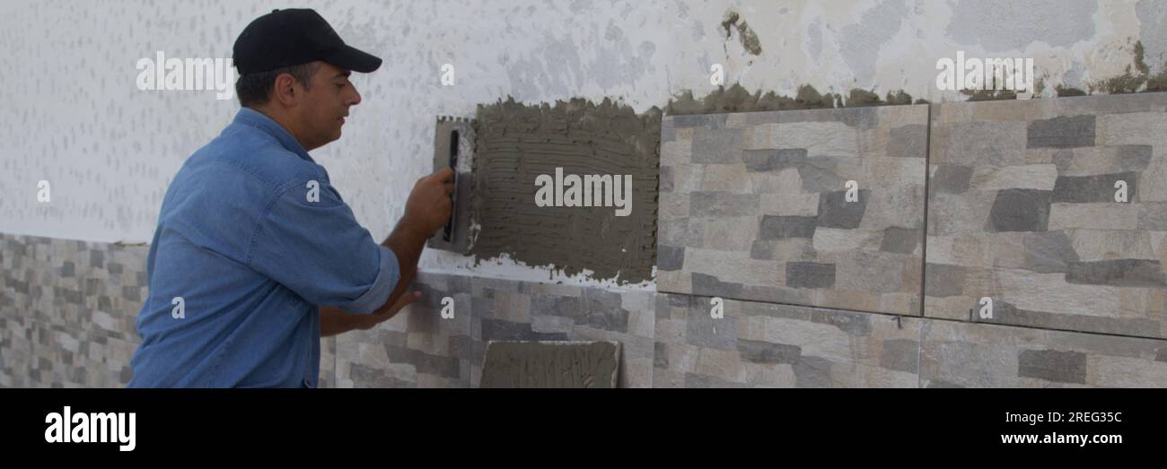 Image of a handyman tiler who with a spatula spreads the glue for ...