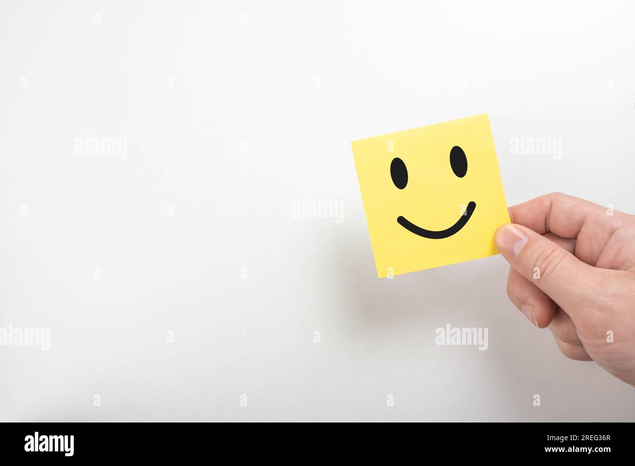 Hand holding yellow paper sticky note smile face on white background ...