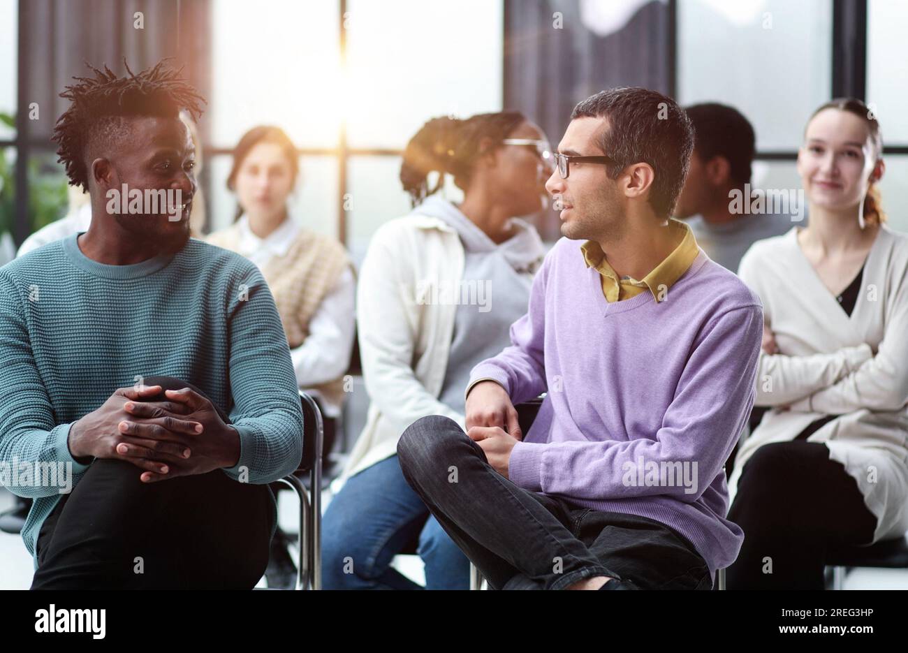 two men communicate while sitting on a chair waiting for a speaker ...