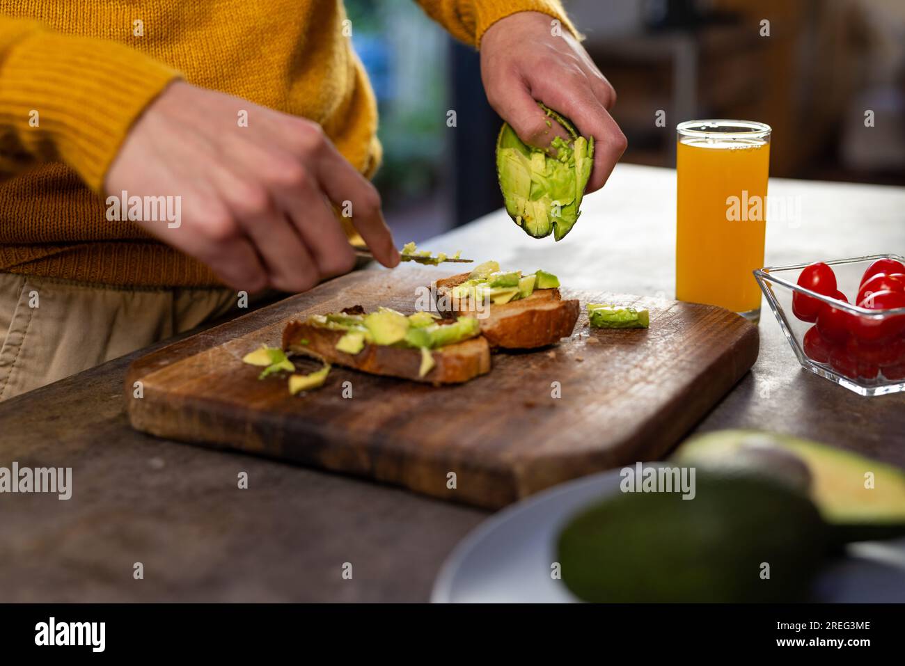 Hands of indian man preparing sandwiches with avocado in kitchen at ...