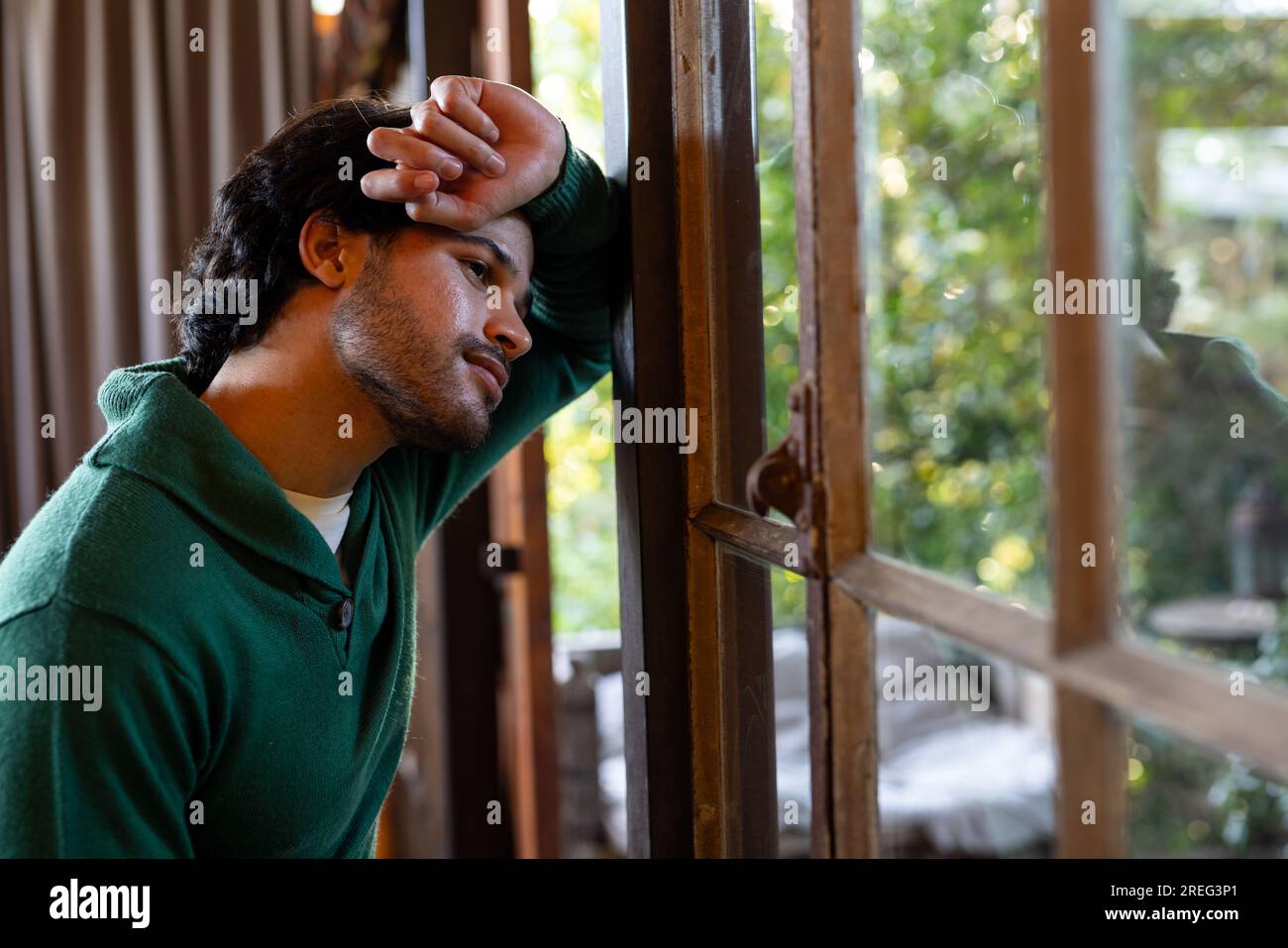 Thoughtful indian man looking out window at sunny home Stock Photo - Alamy