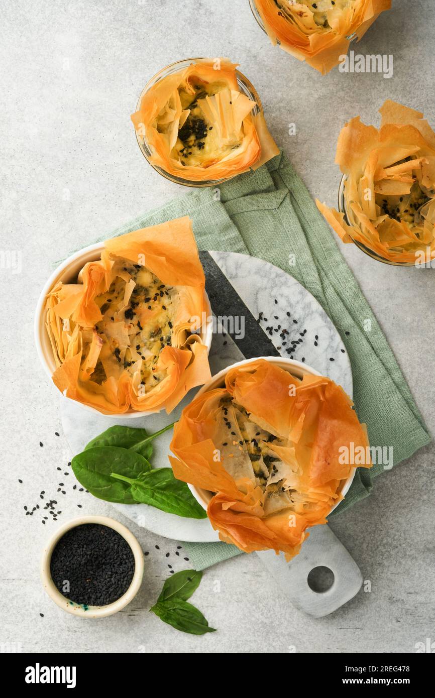 Filo pies with soft feta cheese and spinach in ceramic molds on old ...