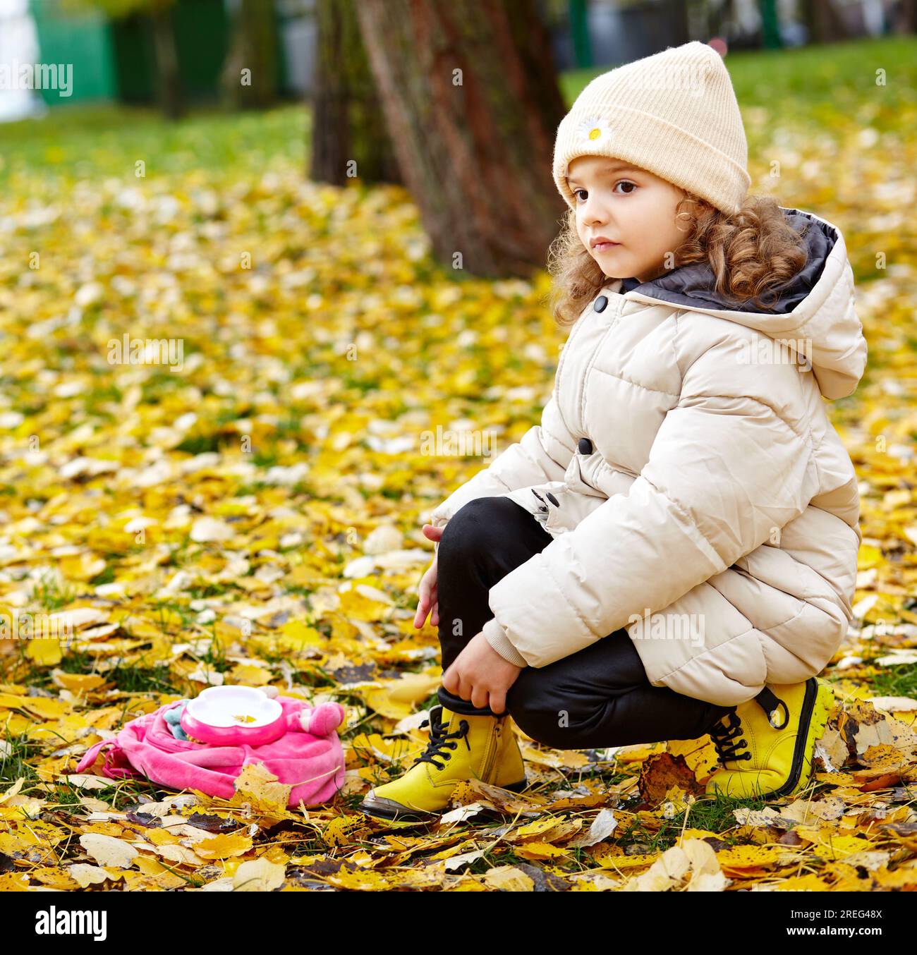 Baby girl are walking in the autumn city park. Little child having fun ...