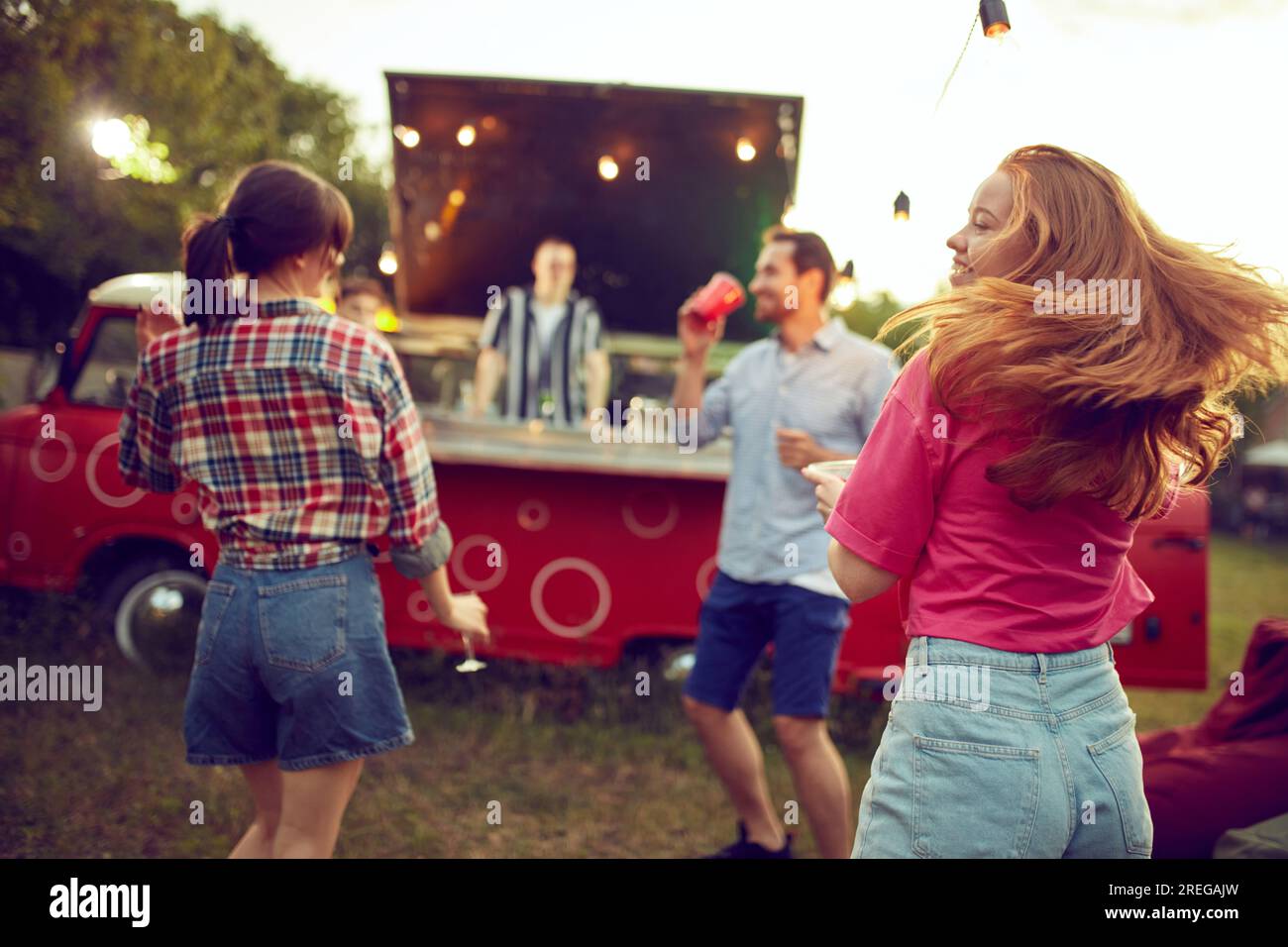 Young people attending outdoor party in countryside dancing, drinking ...