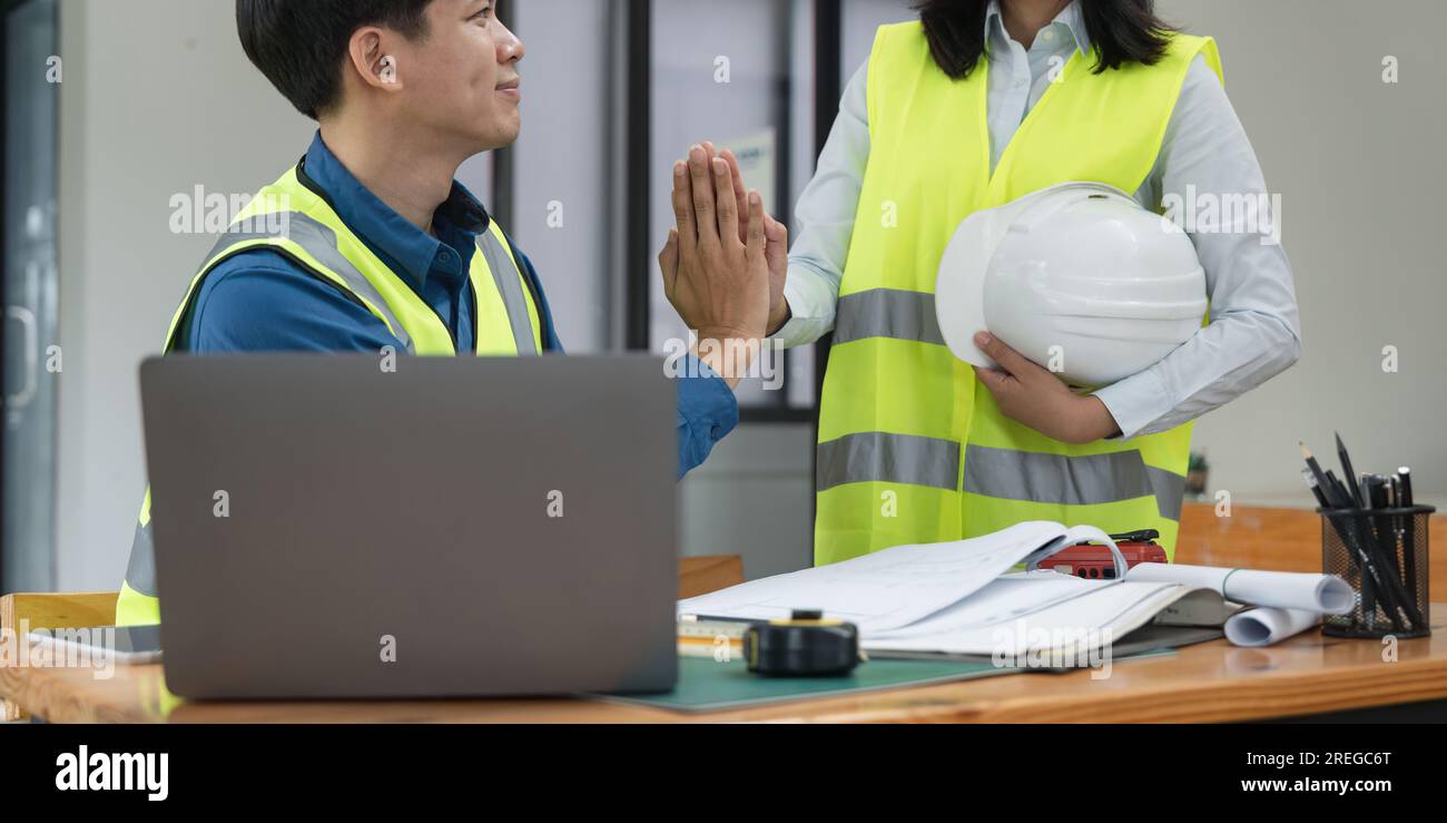 Construction engineer with blueprint making high five while standing on ...
