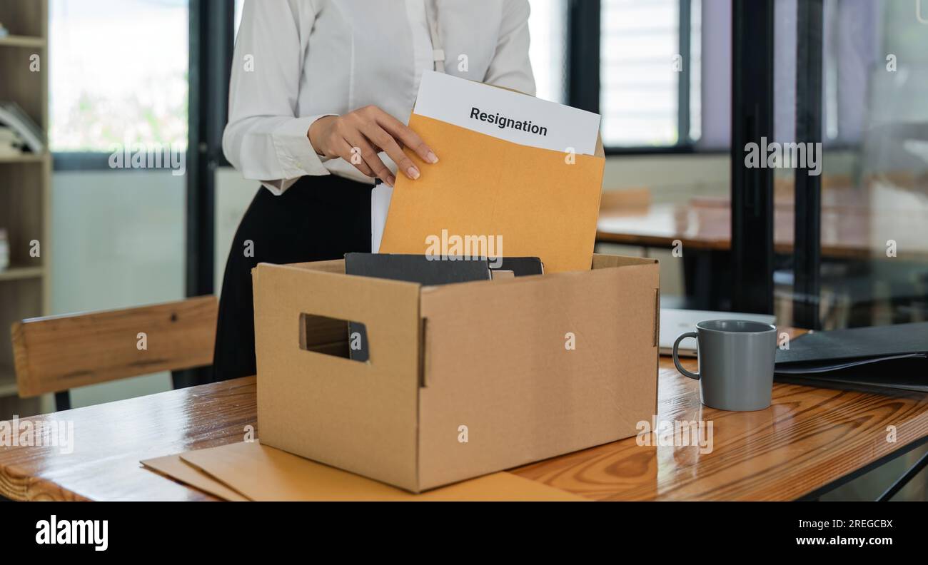 Asian female office worker carrying a cardboard box with her personal ...