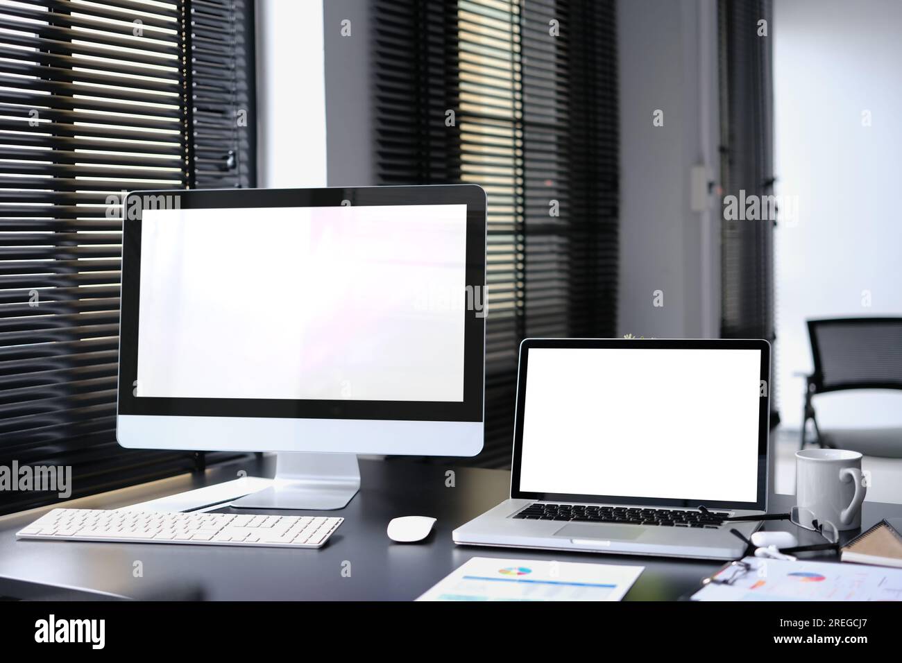 Modern office interior with blank computer monitor, laptop, document ...