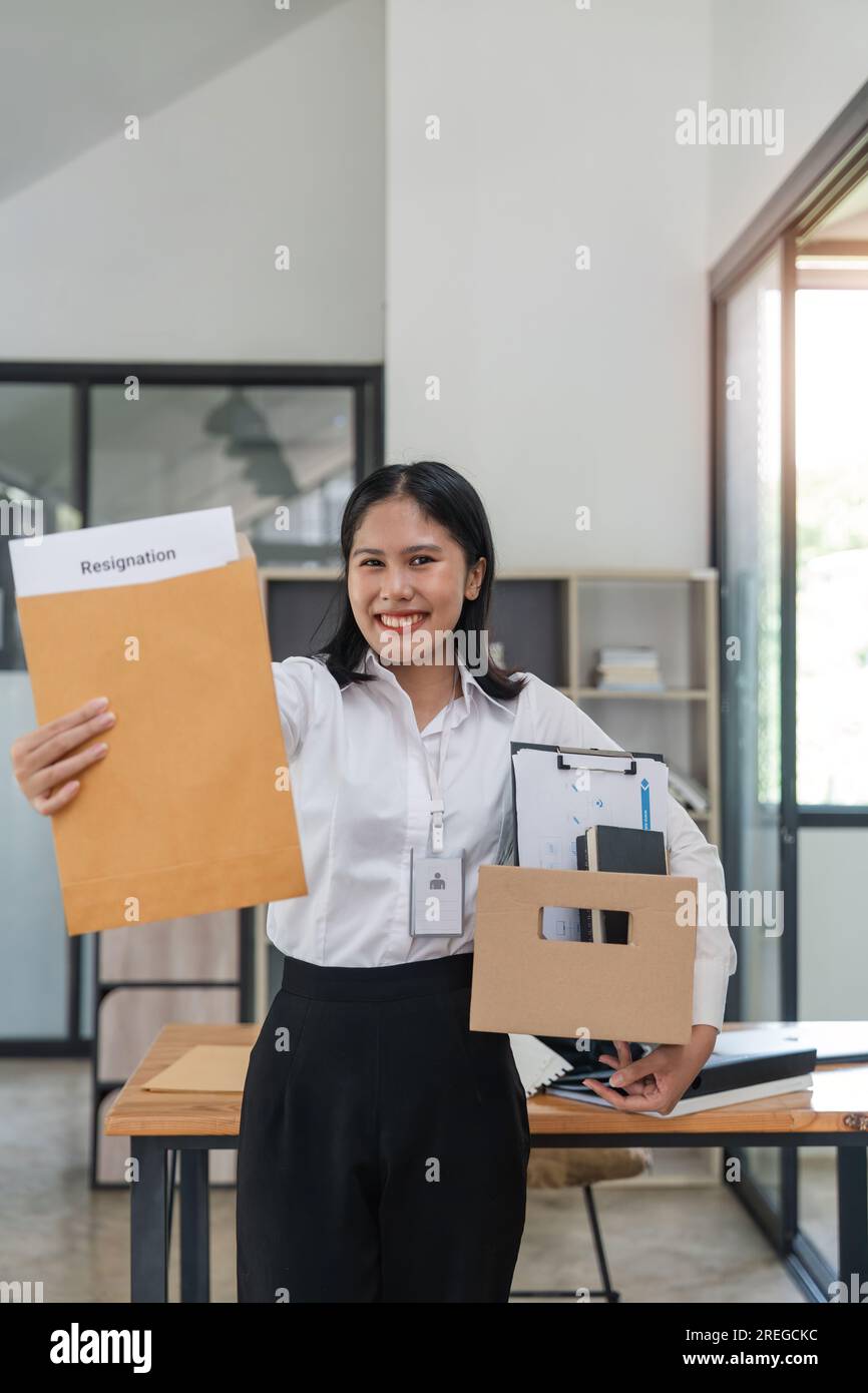 Smiling young Asian female office worker is celebrating her resignation ...