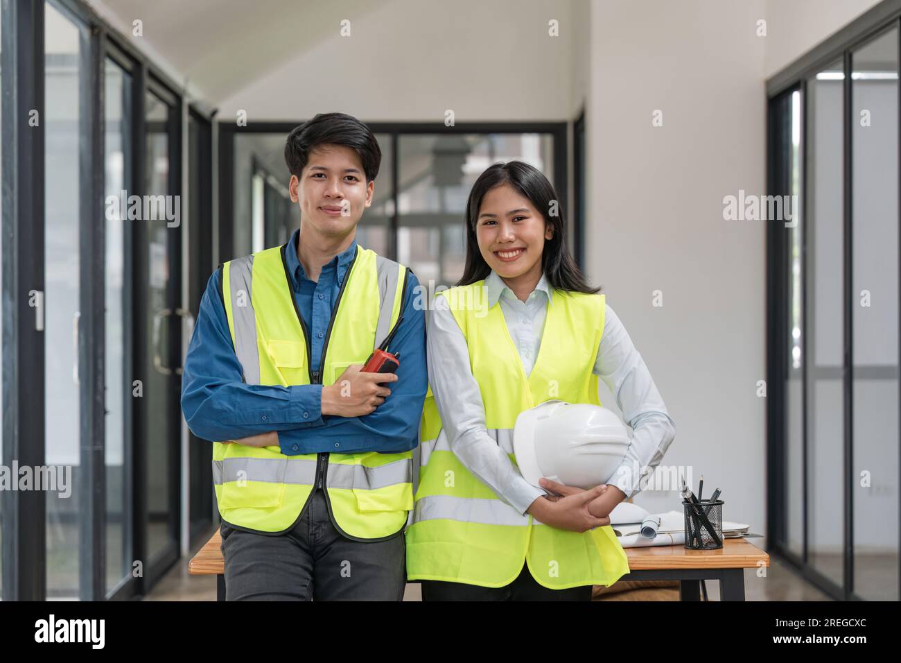 Two engineer workers stand and look at camera with smiling and arm ...
