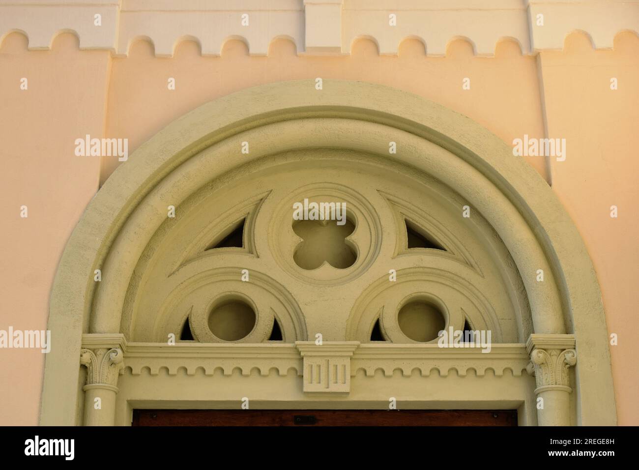 Stone arch above brown wood gates. Ornamental carved classic geometric ...