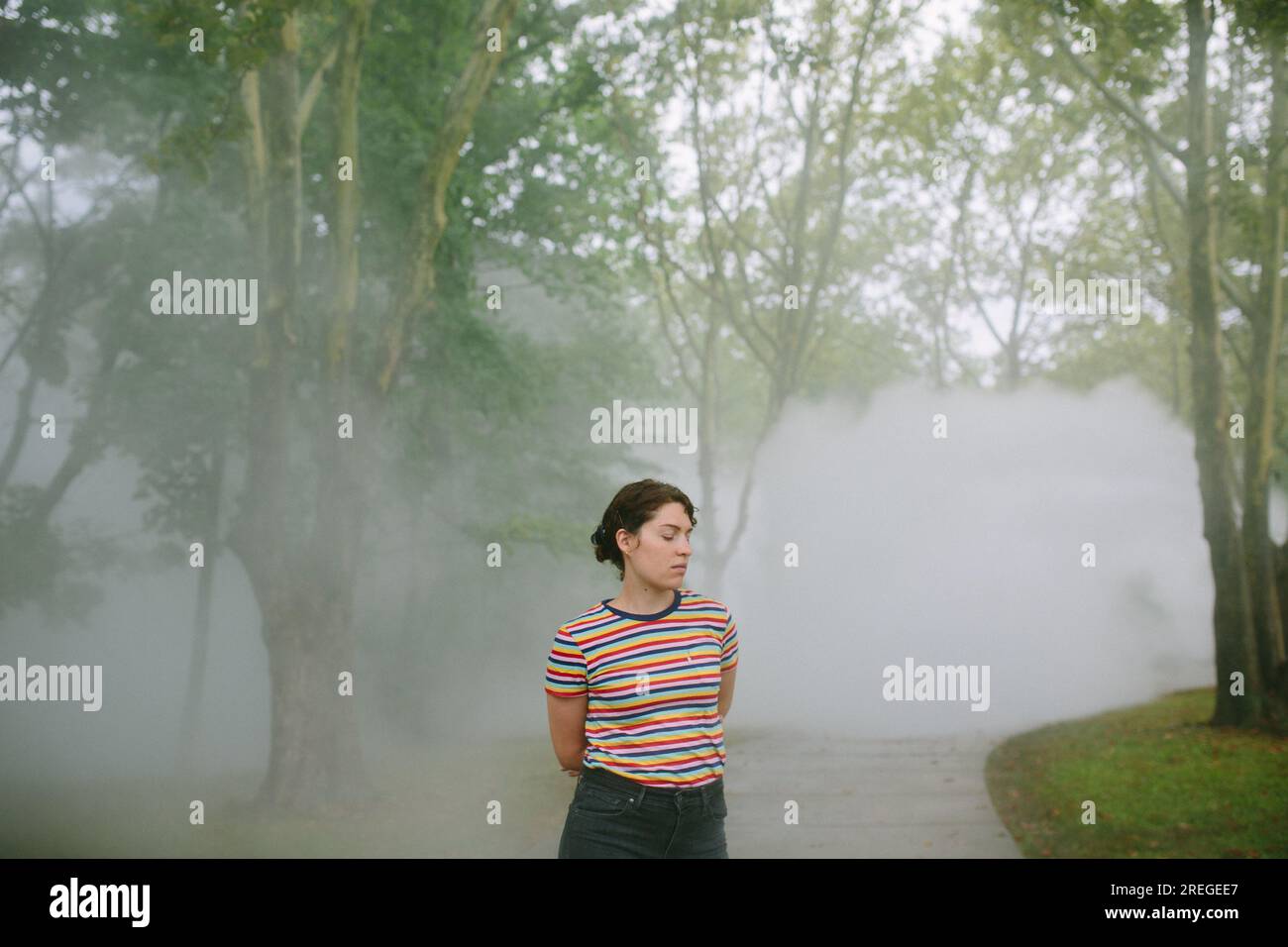 Young woman with downcast eyes standing on a path in a foggy park Stock ...