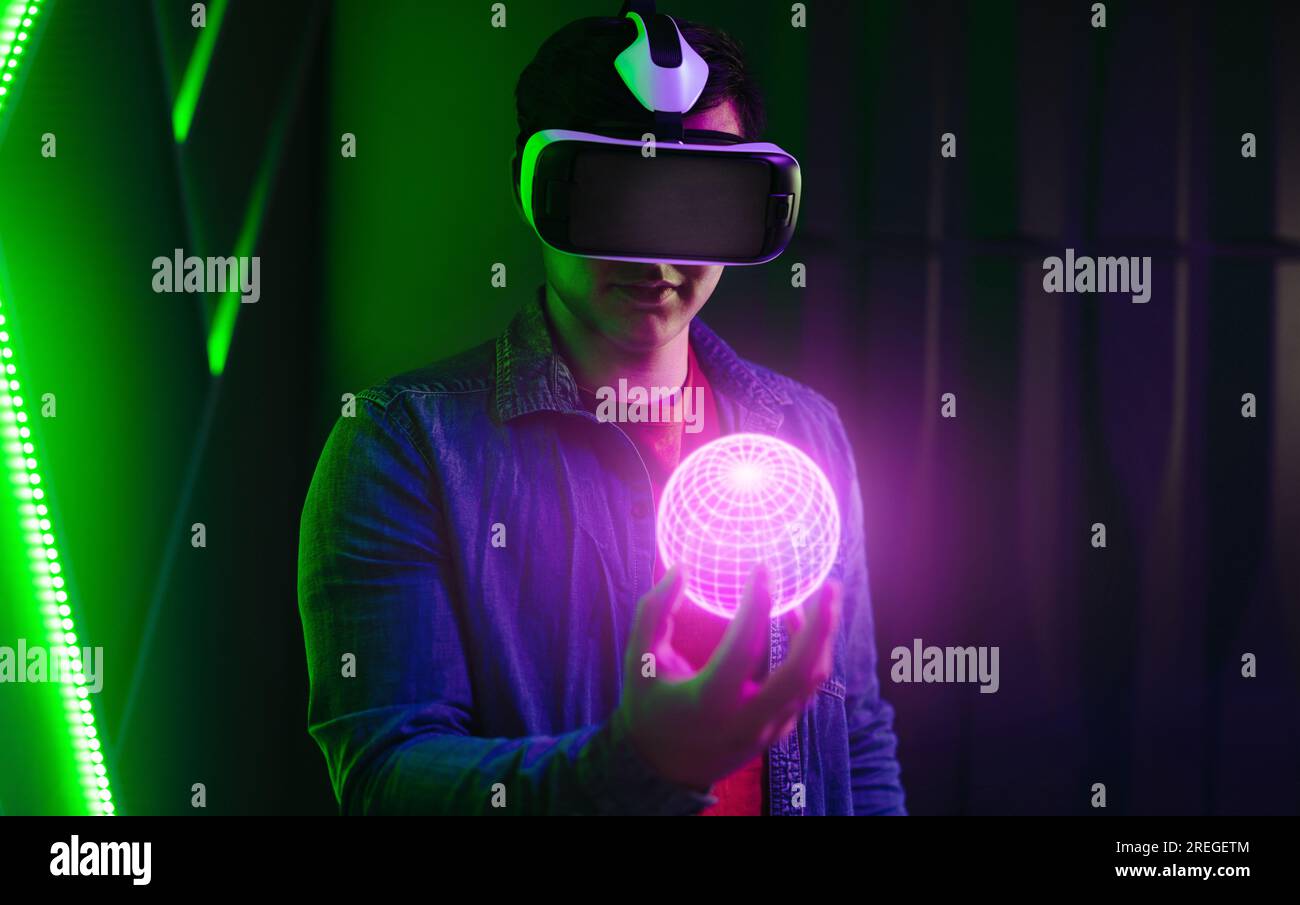 Young man holding a 3D object in a virtual space, exploring the digital world with a VR headset ...
