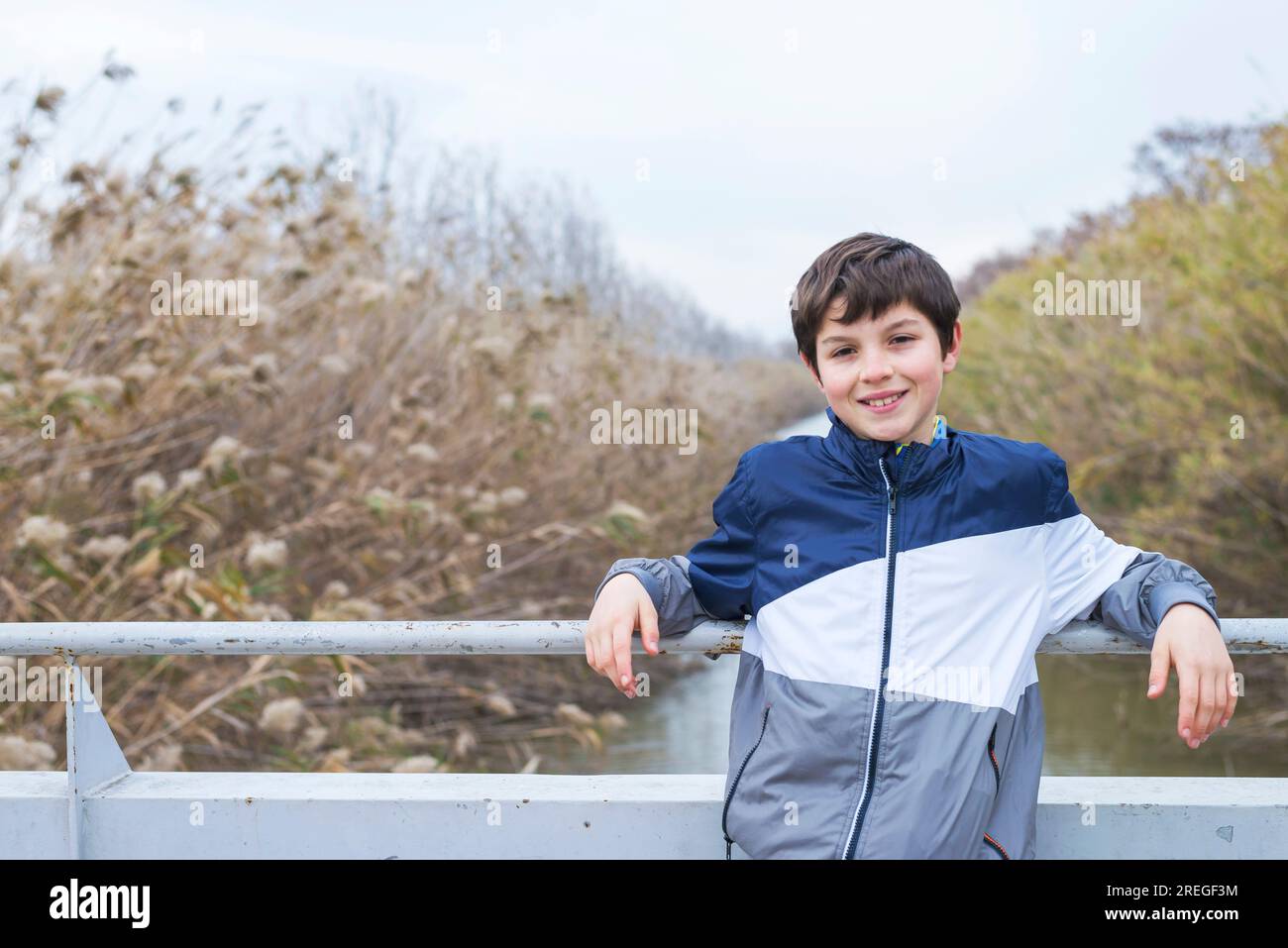 Full length portrait of young teen standing by railing on bridge while ...
