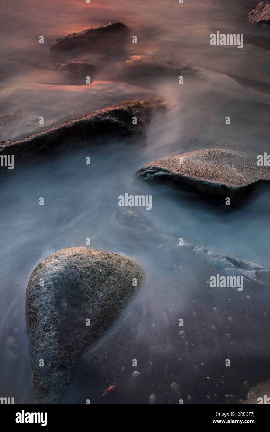 Waves wash around rocks reflecting the colors of sunset Stock Photo - Alamy