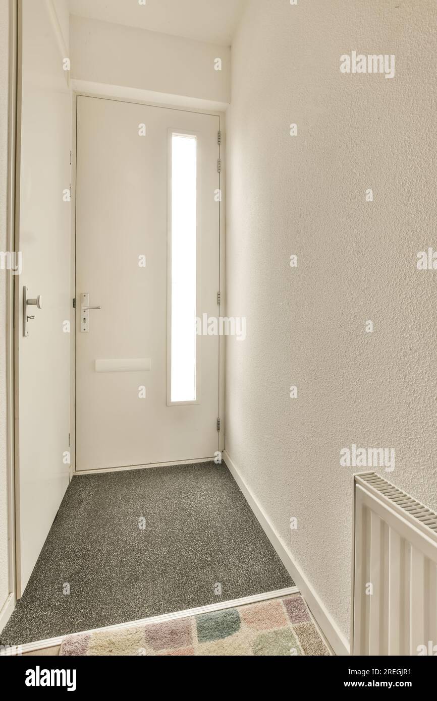 an empty hallway with white walls and black carpeting, there is a door ...