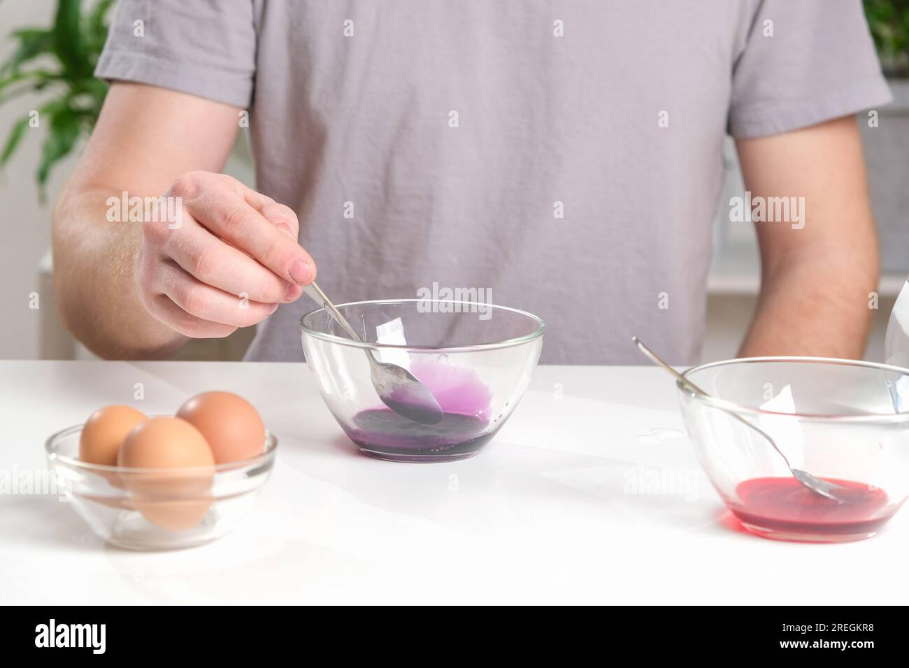 A man pours a spoonful of water into a glass cup with dye. Dyeing ...