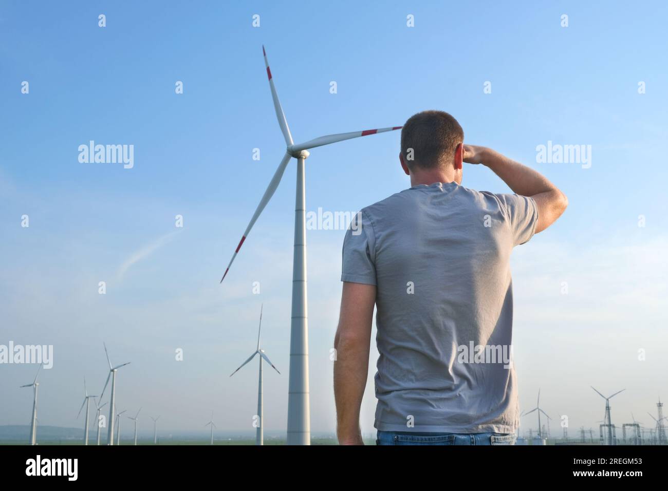 The man stands with his back and looks at the wind turbine. Wind Energy ...