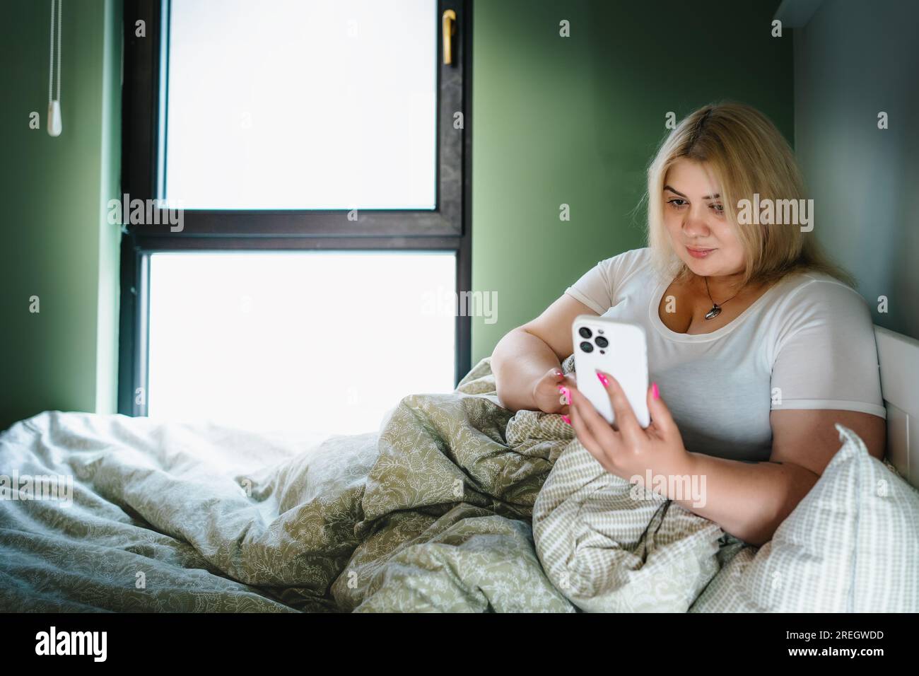 Plus size woman use mobile phone lying in bed. Overweight lady have ...