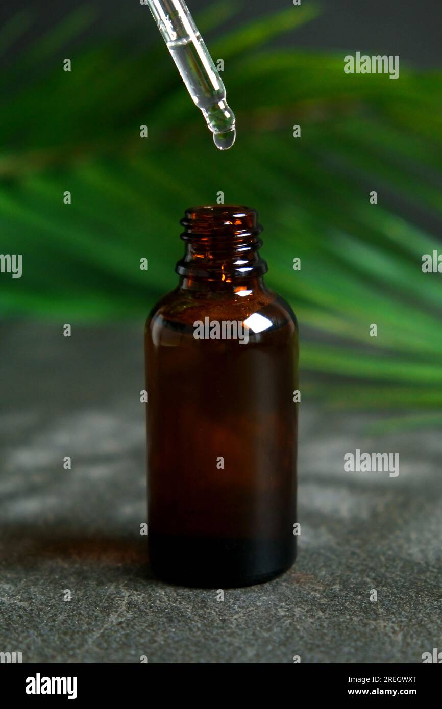Drop of clear liquid, oil, serum or tincture dripping from pipette in ...