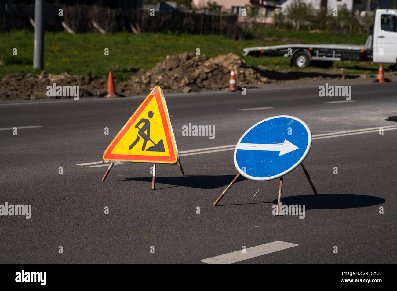 Blue and yellow-red safety signs warning about road works.The road is ...
