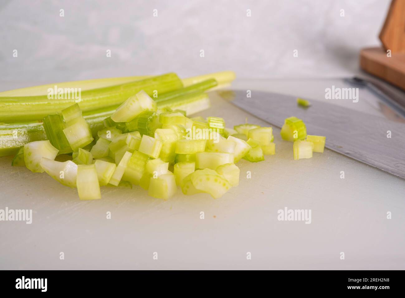 Green Celery Being Sliced on White Cutting Board With Chef's Knif and ...