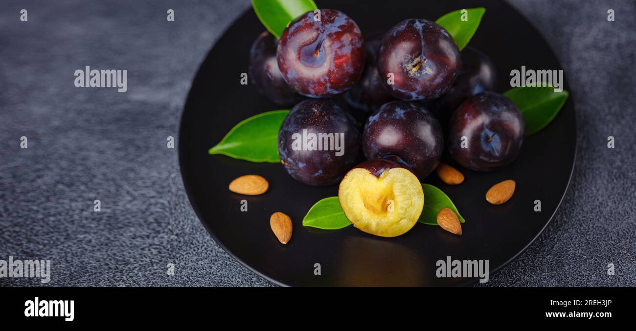 Sweet plums on dark background. Fresh blue plums with leaves. Food ...