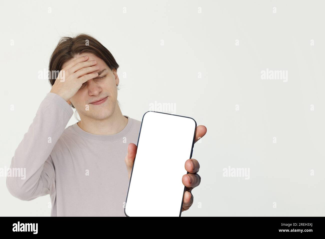 Confused young adult man showing blank cell phone with empty white ...
