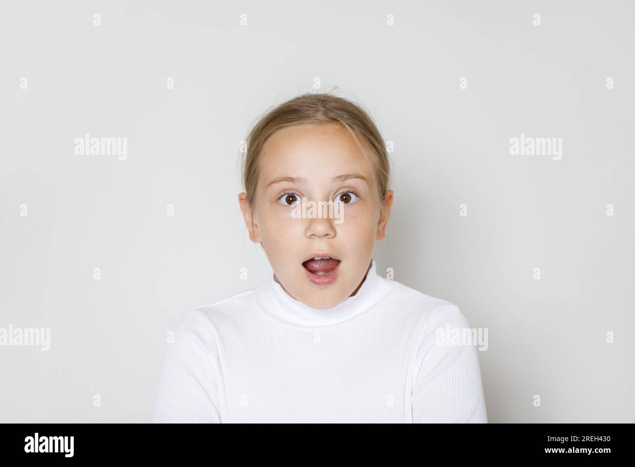 Shocked excited child girl with opened mouth on white color background ...