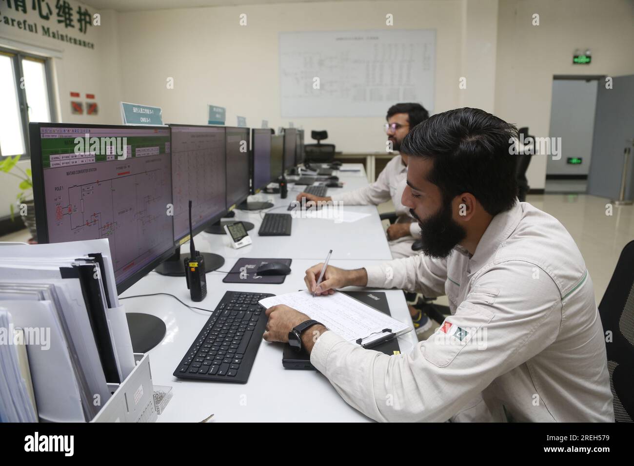Lahore, Pakistan. 4th July, 2023. Zubair Tufail (front) works in the control room at a converter ...