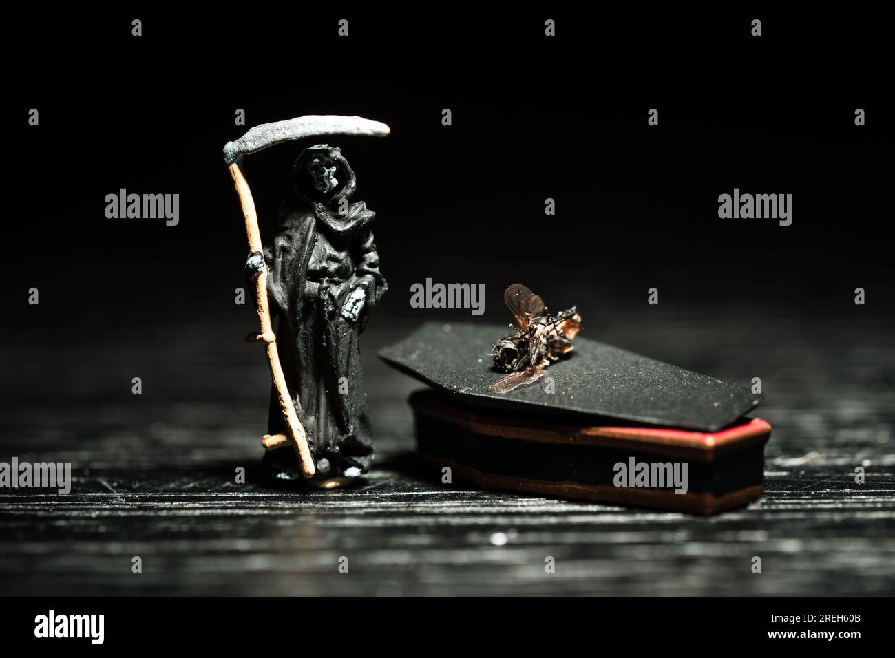 Miniature Death carrying scythe next to a coffin on a dark black ...