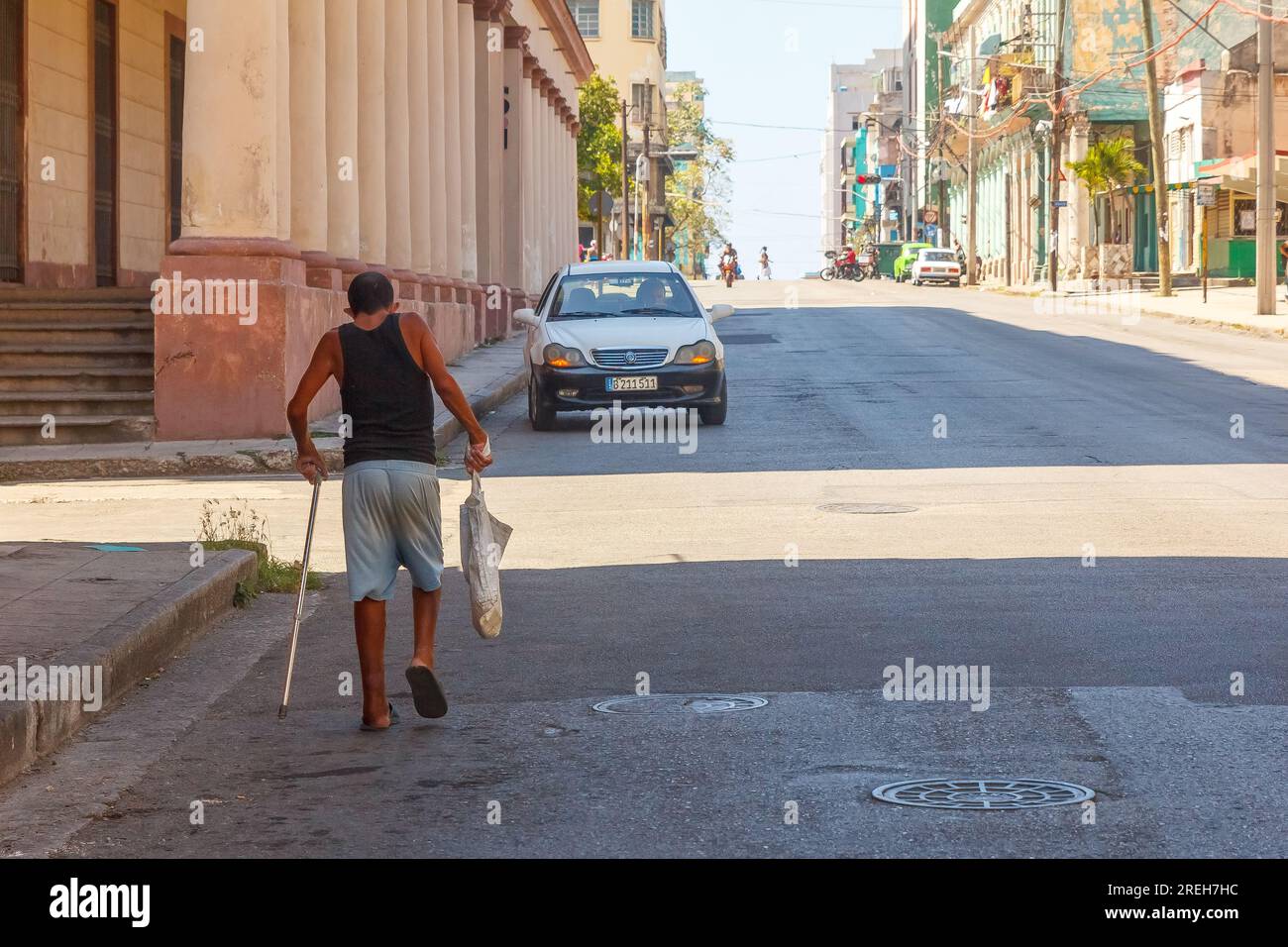 Havana, Cuba, A senior Cuban man walks with a cane and a bag in a city ...