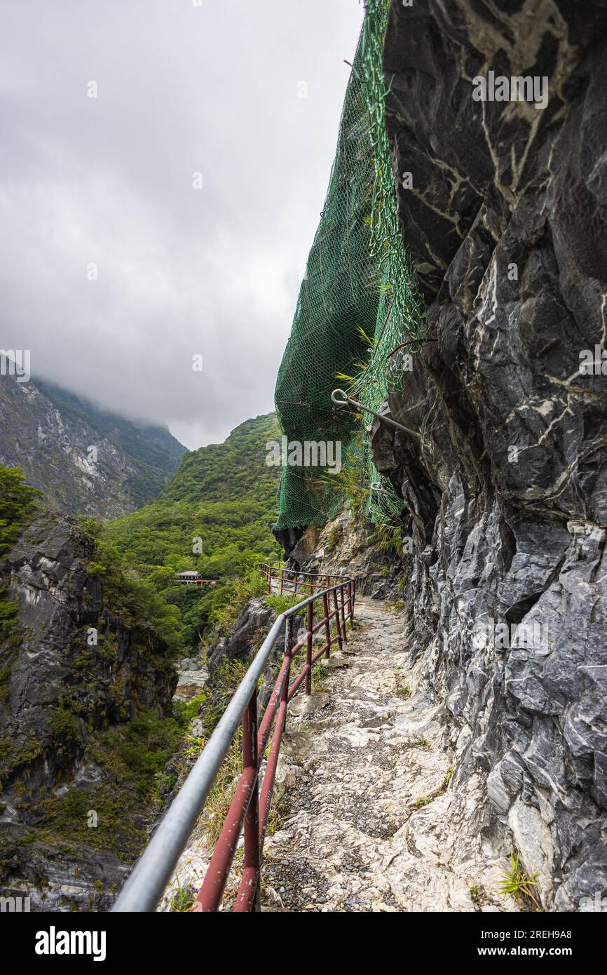 The narrow hiking trail clings to the edge of the cliff, offering a ...
