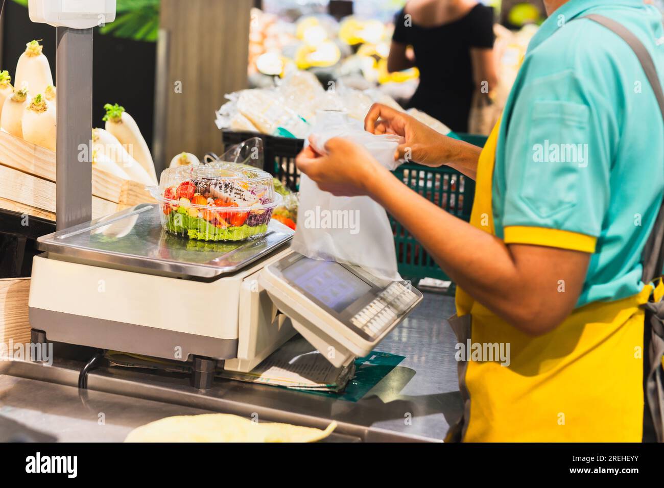 Grocery Store staff weighing fresh salas in plastic box on digital ...