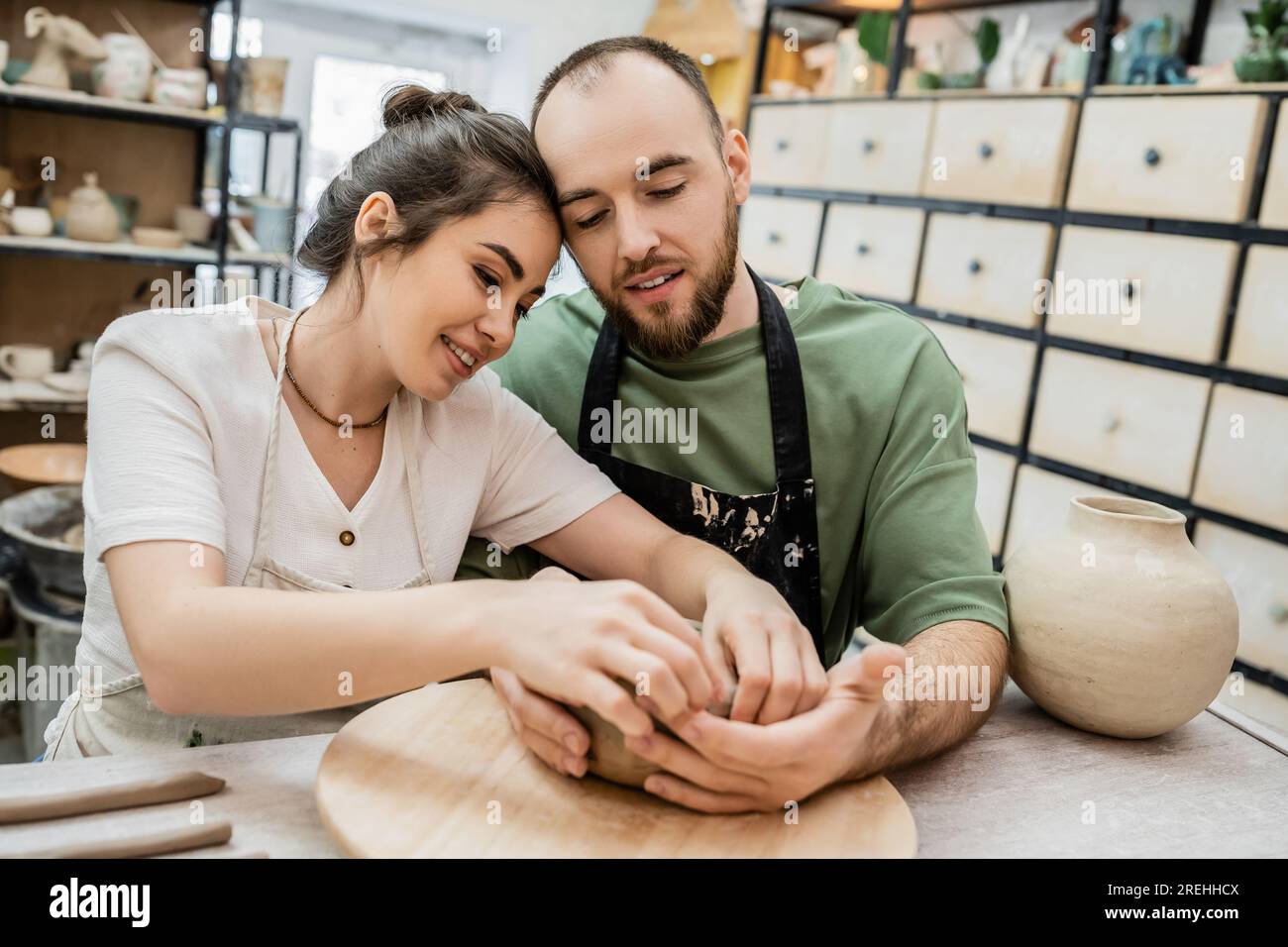 Positive romantic couple of potters making clay bowl in ceramic ...