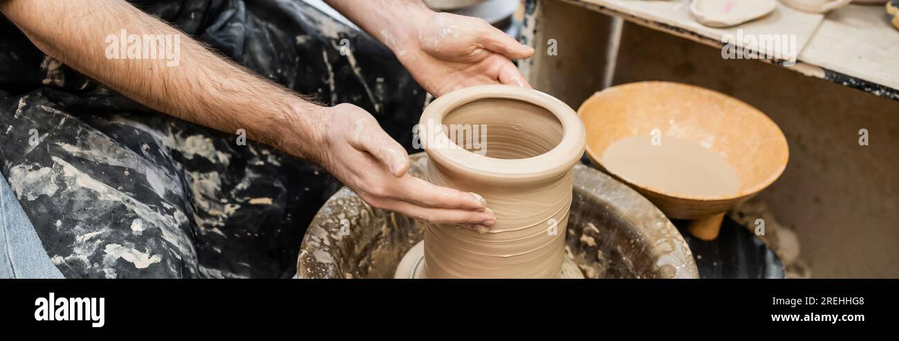 banner, Cropped view of sculptor shaping clay on pottery wheel in ...