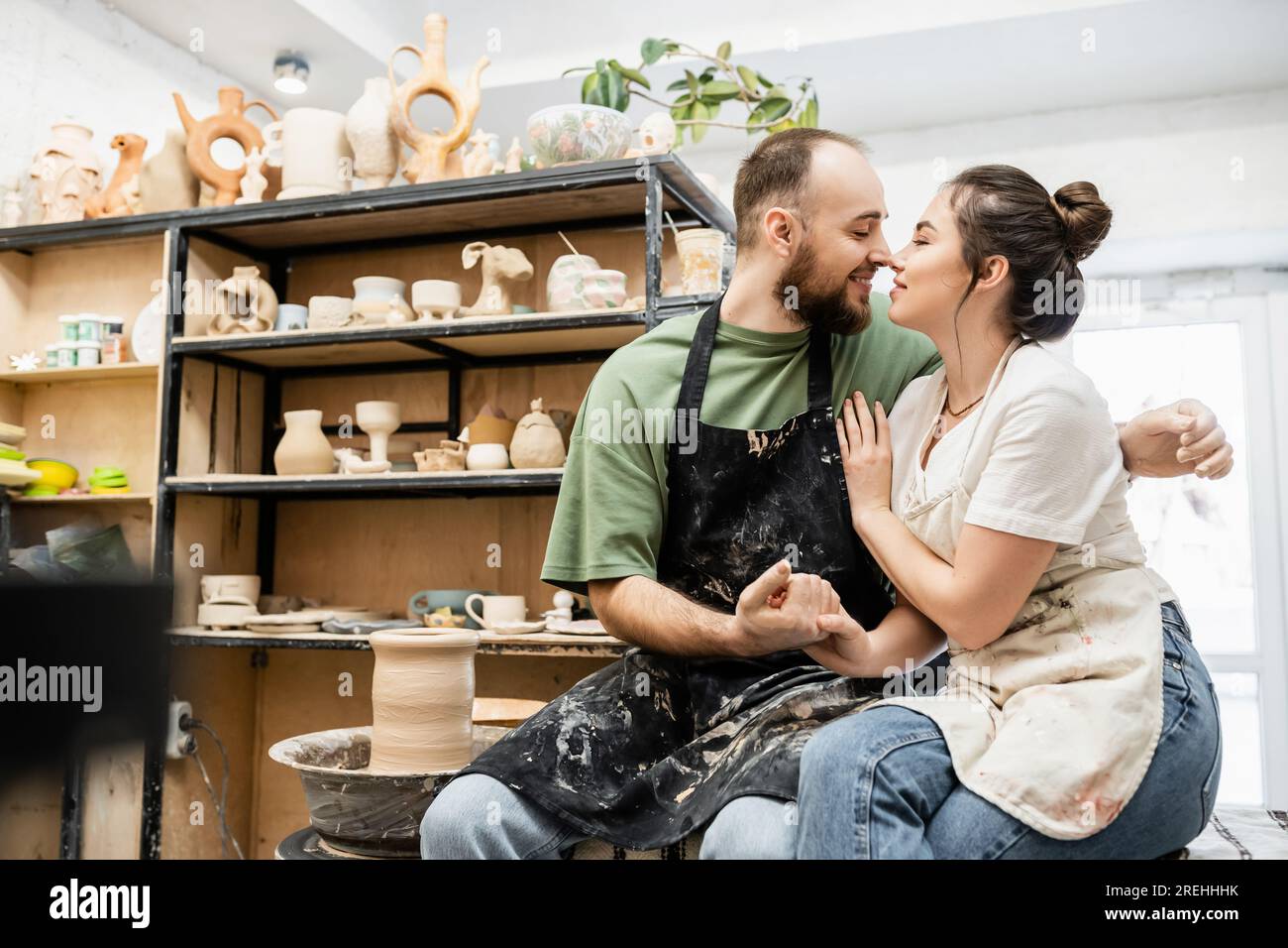 Side view of couple of artisans in aprons holding hands and smiling ...