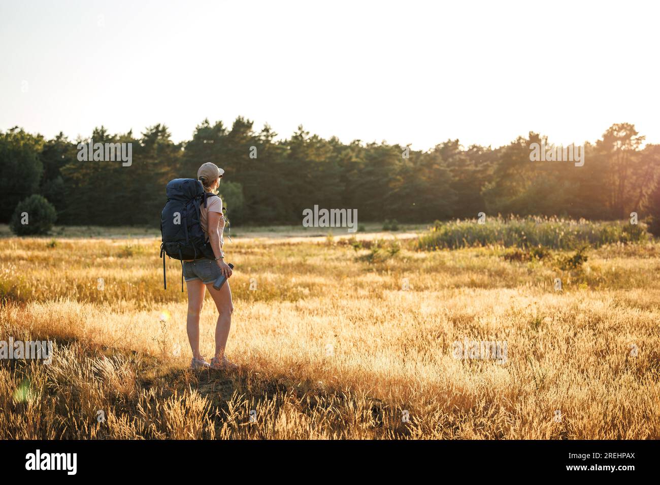 Female hiker with backpack and thermos is resting in nature and ...